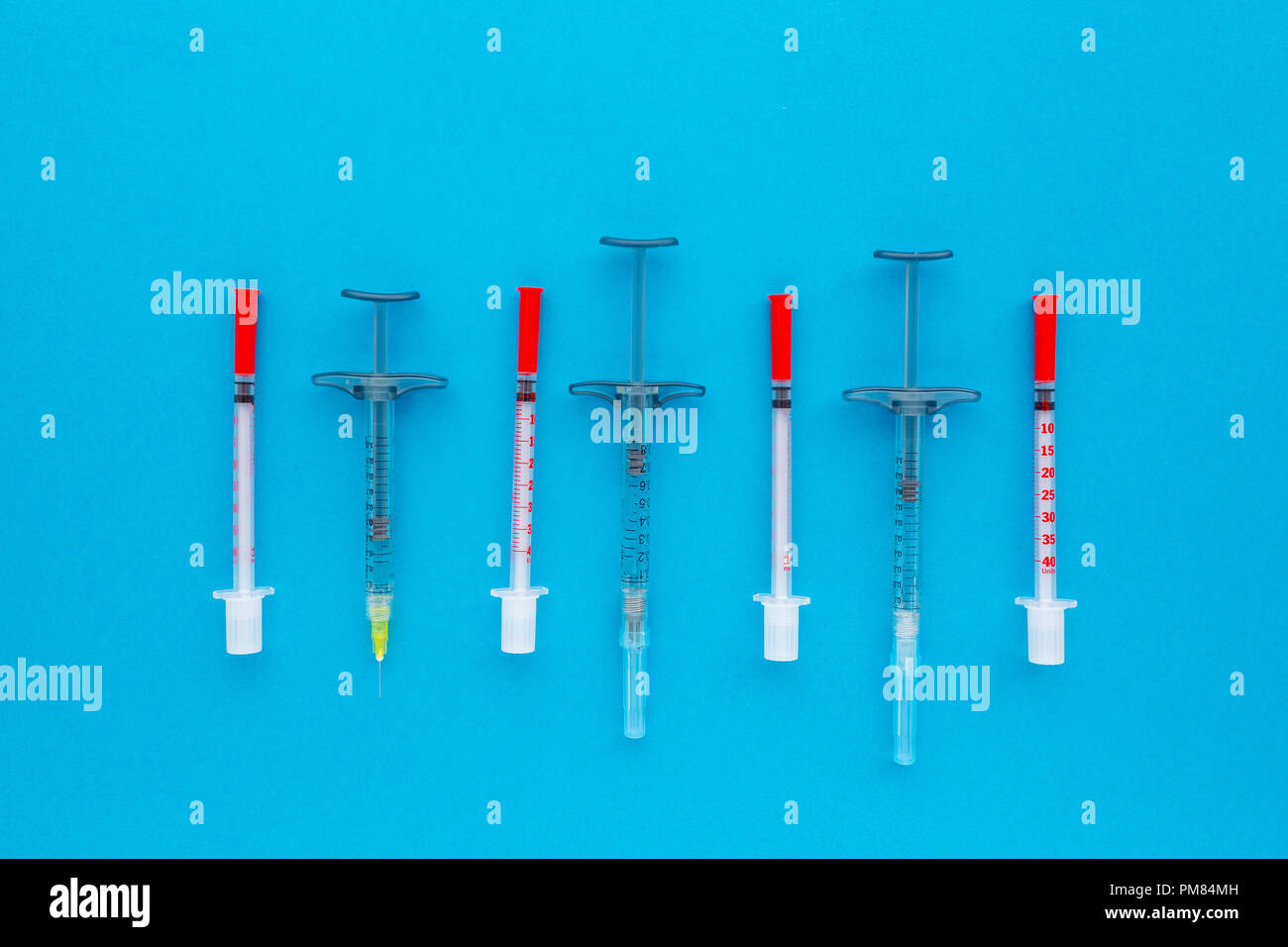 Syringes organized in a row over blue background, top view. Mock up ...