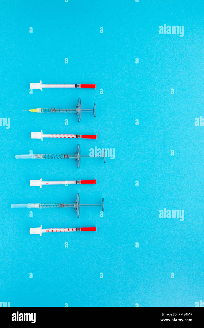 Syringes organized in a row over blue background, top view. Mock up ...