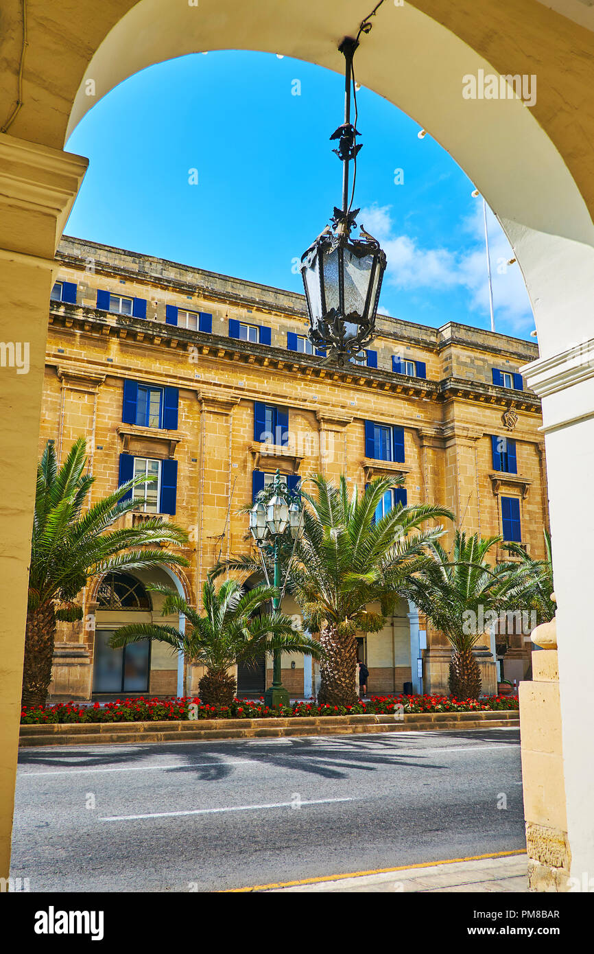 The scenic view through the arch on the green palms and stone edifice ...