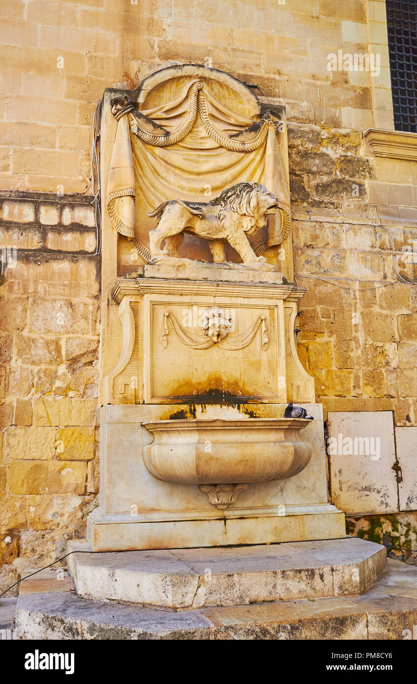 The medieval limestone Lion fountain is built in wall of St John Co ...