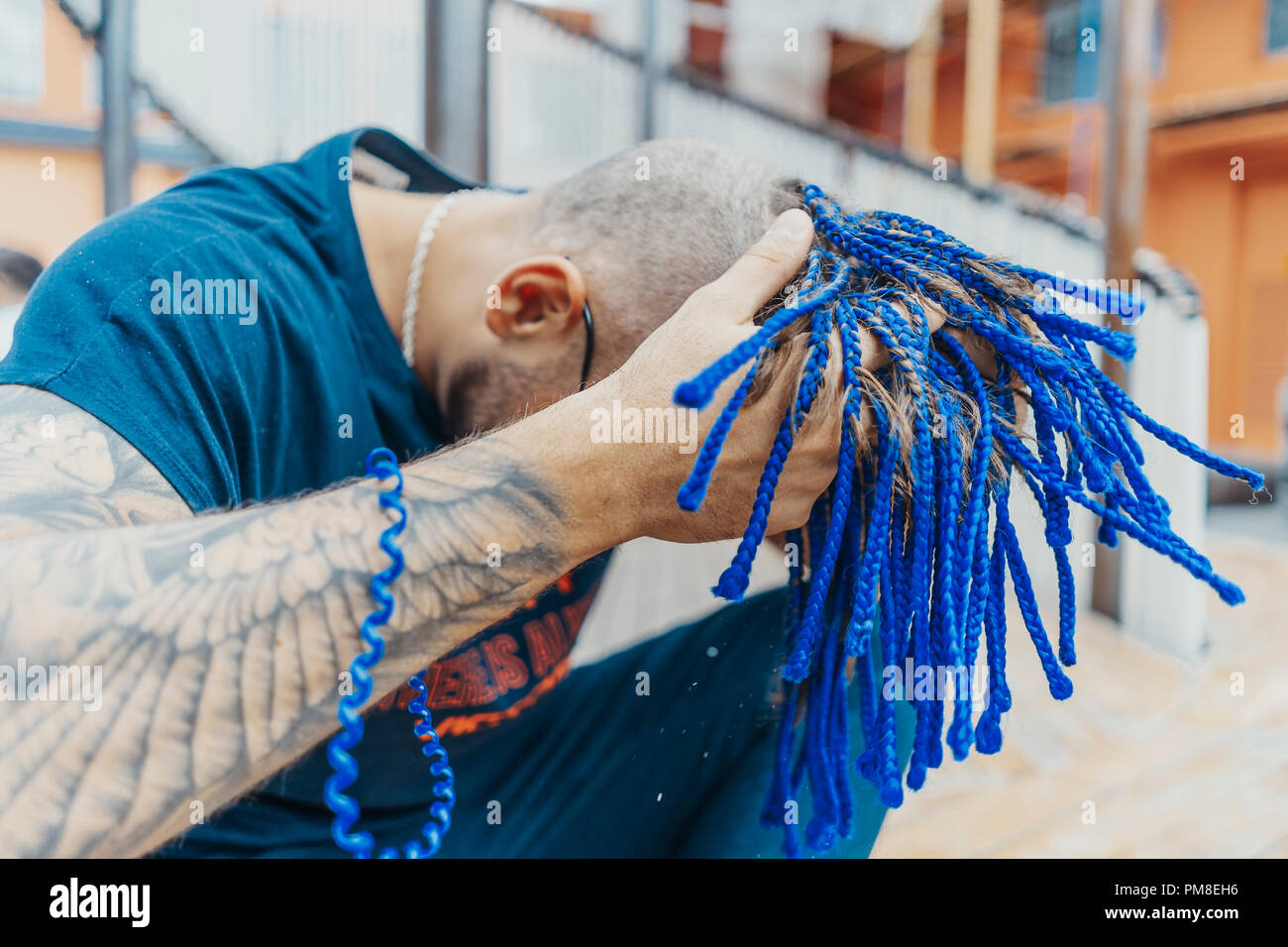 Young attractive man with blue dreadlocks touching his hair Stock Photo ...