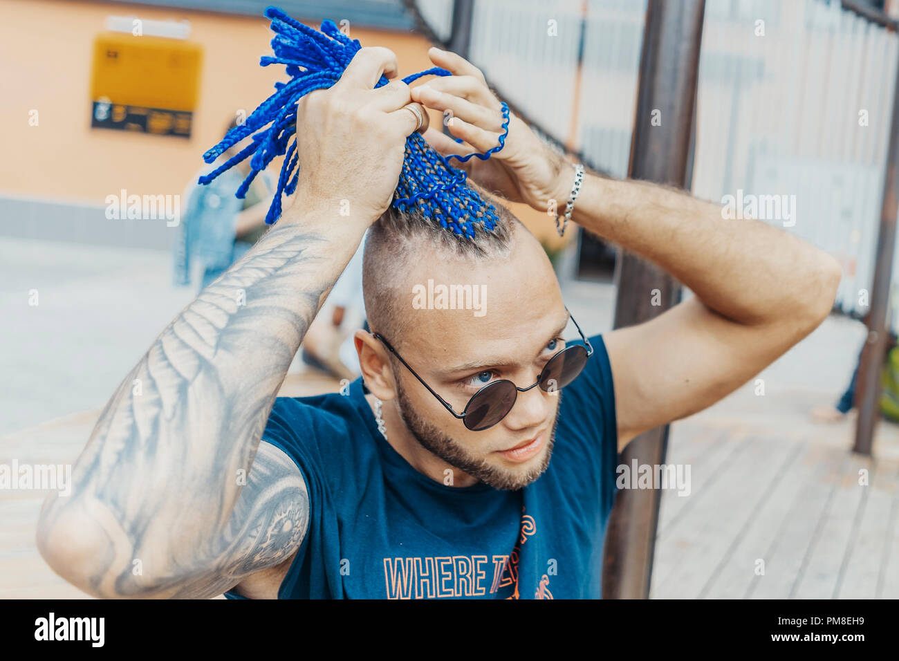 Young attractive man with blue dreadlocks touching his hair Stock Photo ...