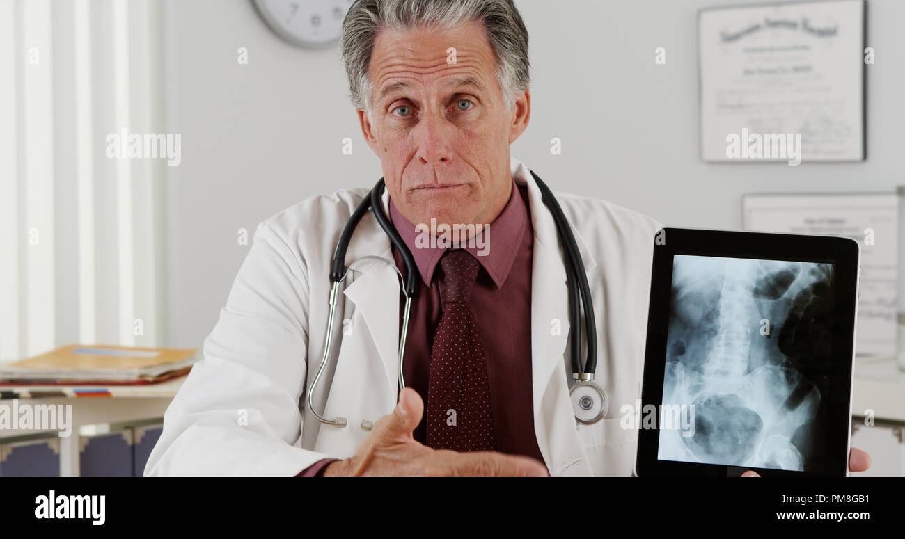 Senior doctor talking to camera with xray Stock Photo - Alamy
