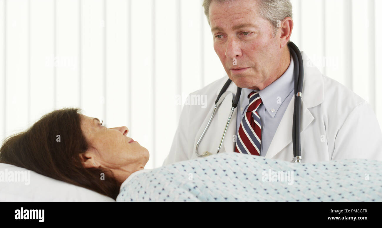 Senior doctor talking and making patient smile Stock Photo - Alamy