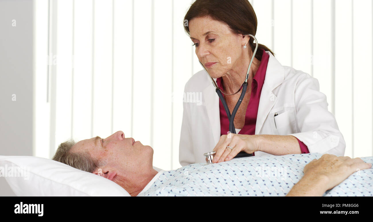 Senior doctor listening to mature patient's heart Stock Photo - Alamy