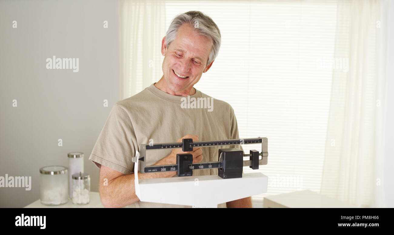 Portrait of happy middle-aged man with his weight on scale Stock Photo ...