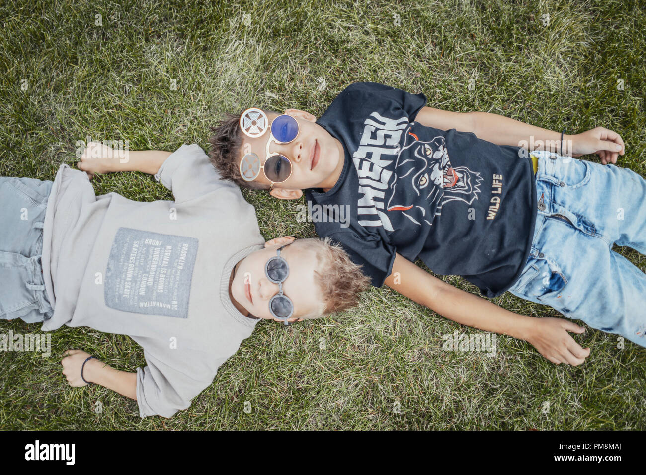 Close up of boys, brothers lying in the park on green grass. View from ...