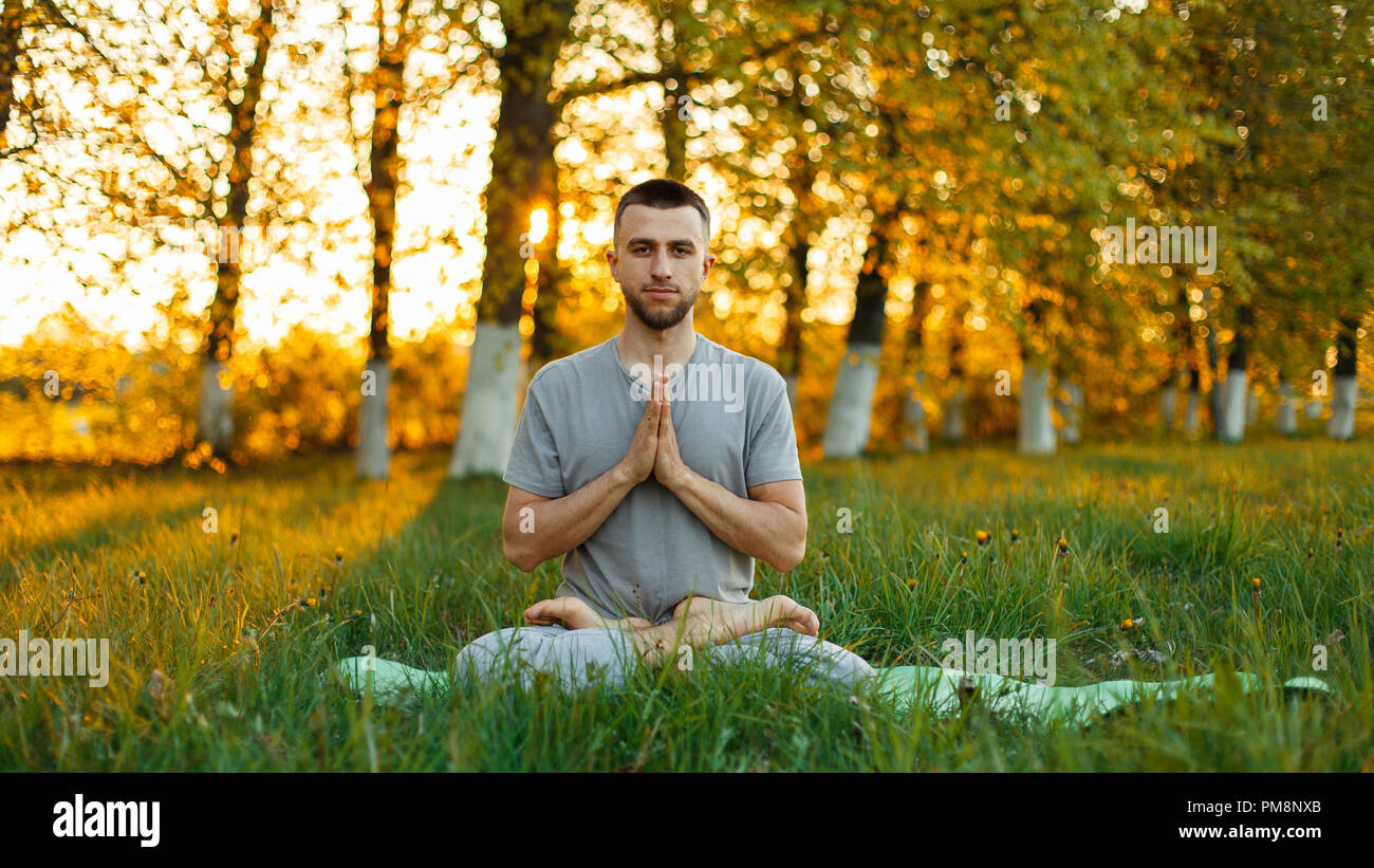 Man meditating in a park at sunset. Healthy lifestyle Stock Photo - Alamy