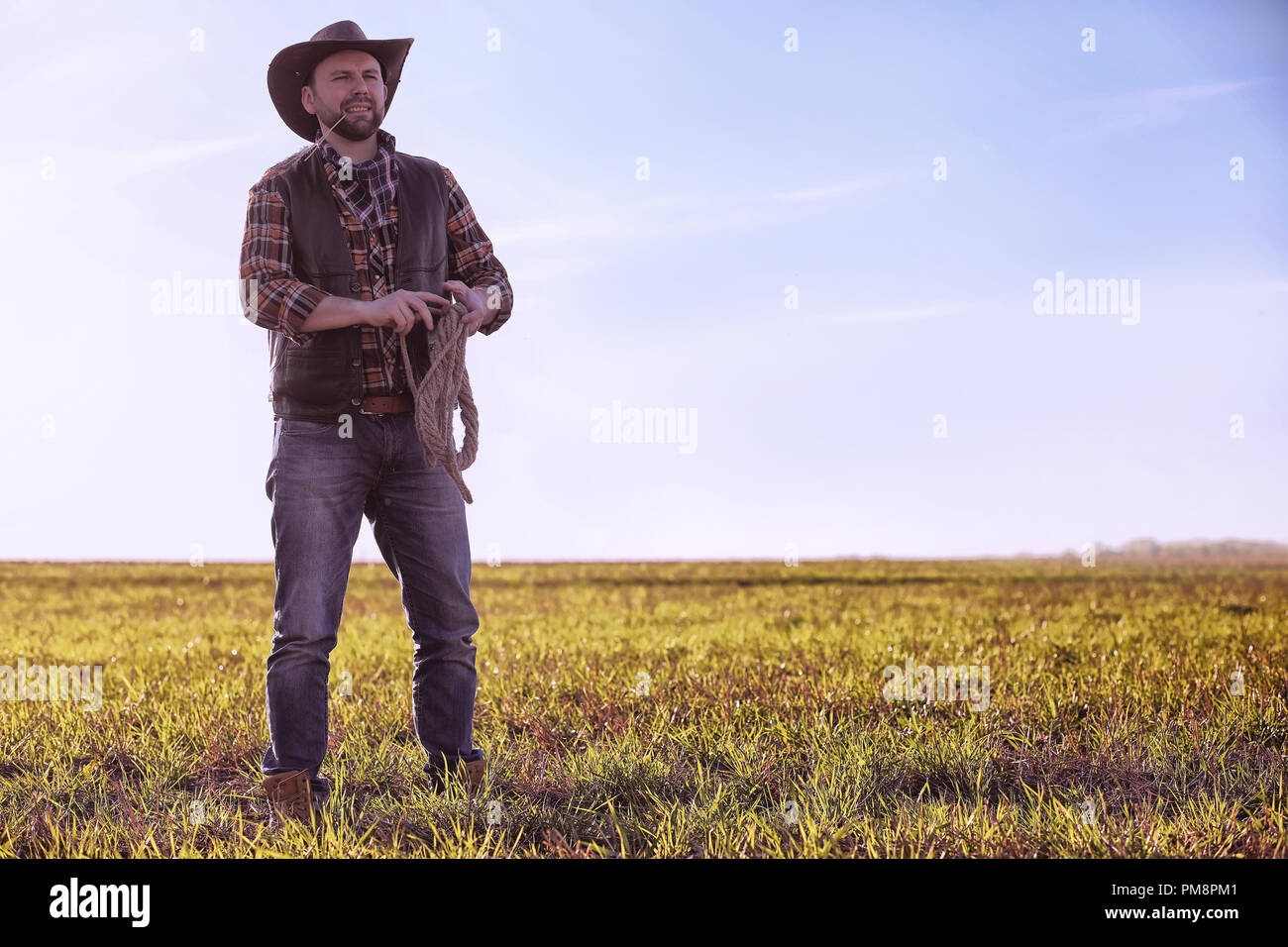 Cowboy standing in a field at sunset Stock Photo - Alamy