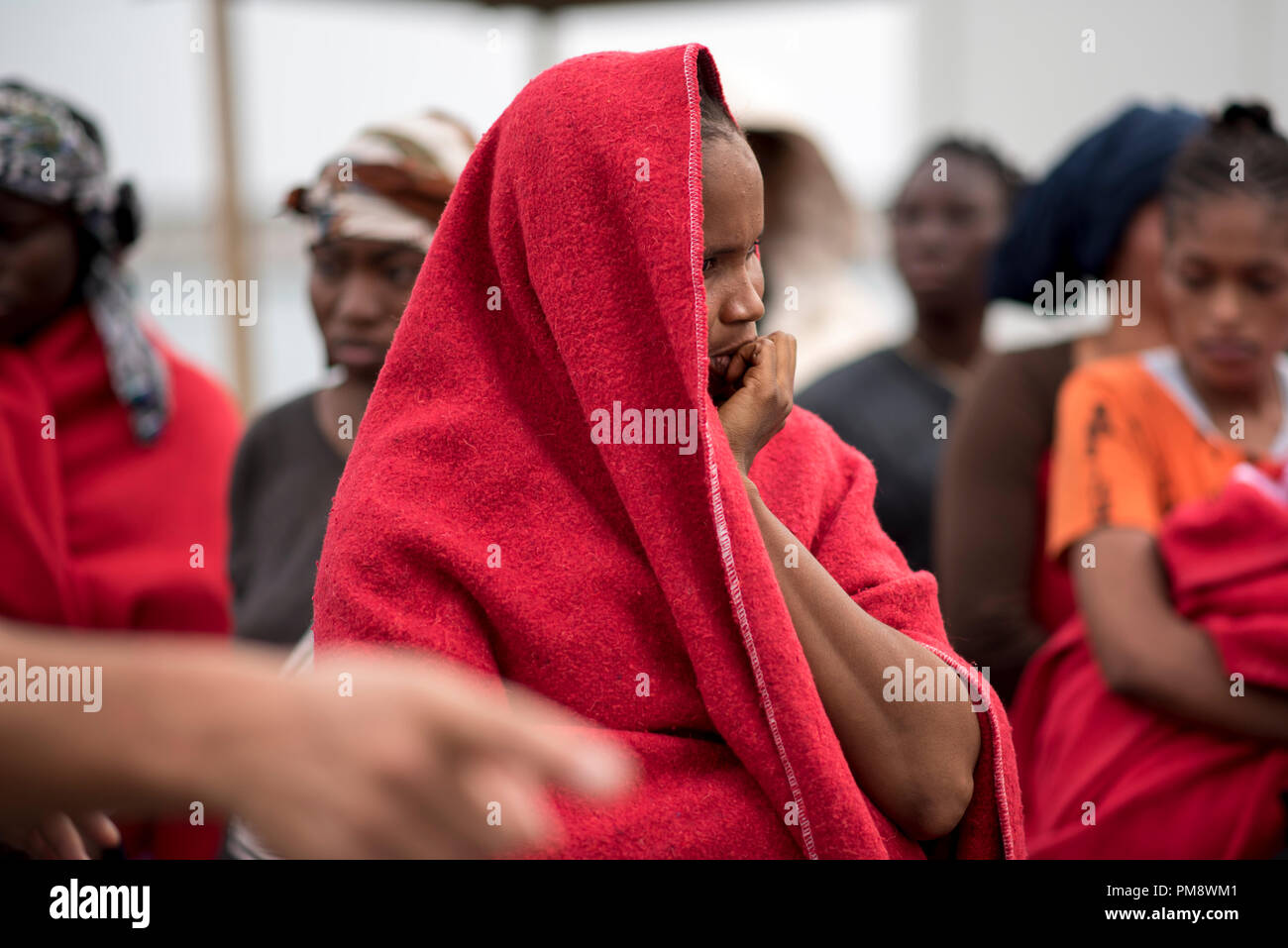 Sub Saharan woman seen covered with a red blanket after being rescued ...