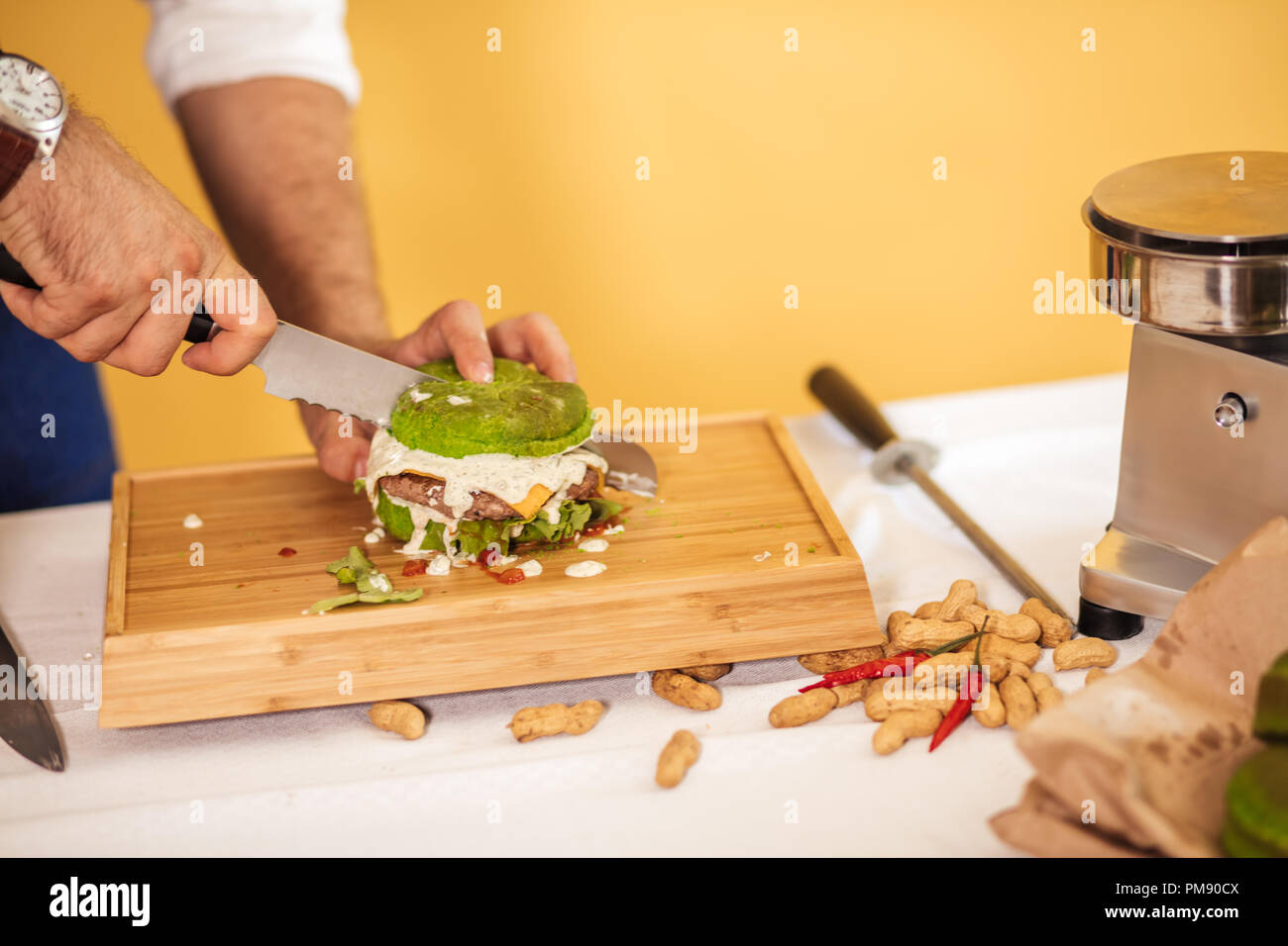 Chef cutting burger into two halfs to perform quality ingredients Stock ...