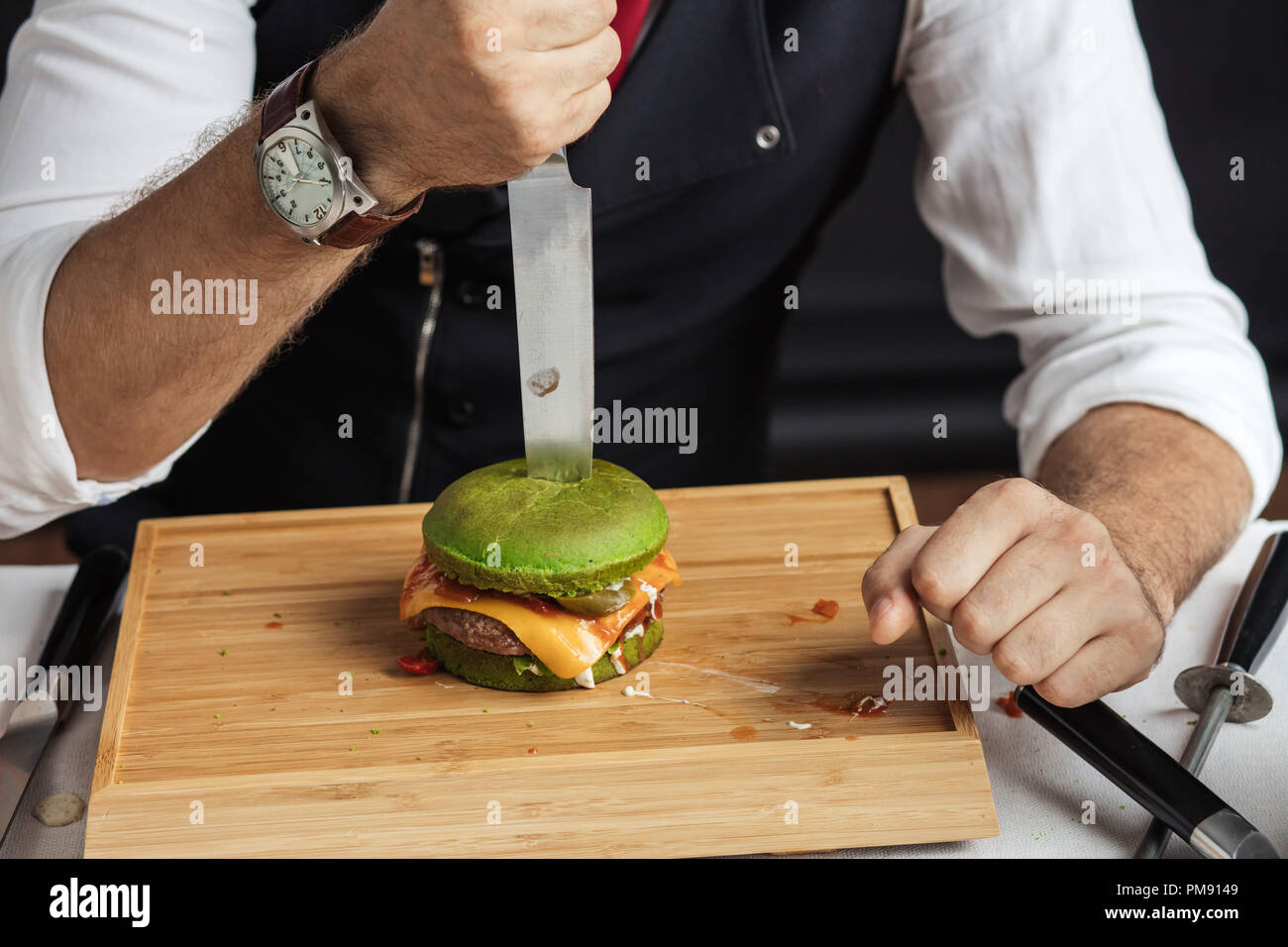 Process of eating burgers. Master Cook cutting tasty hamburger with ...