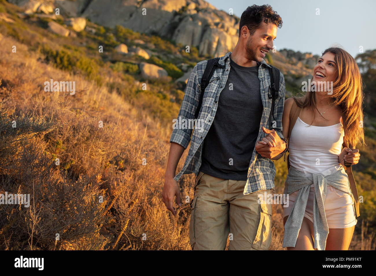 Young man with his girlfriend walking through a mountain trail. Happy ...