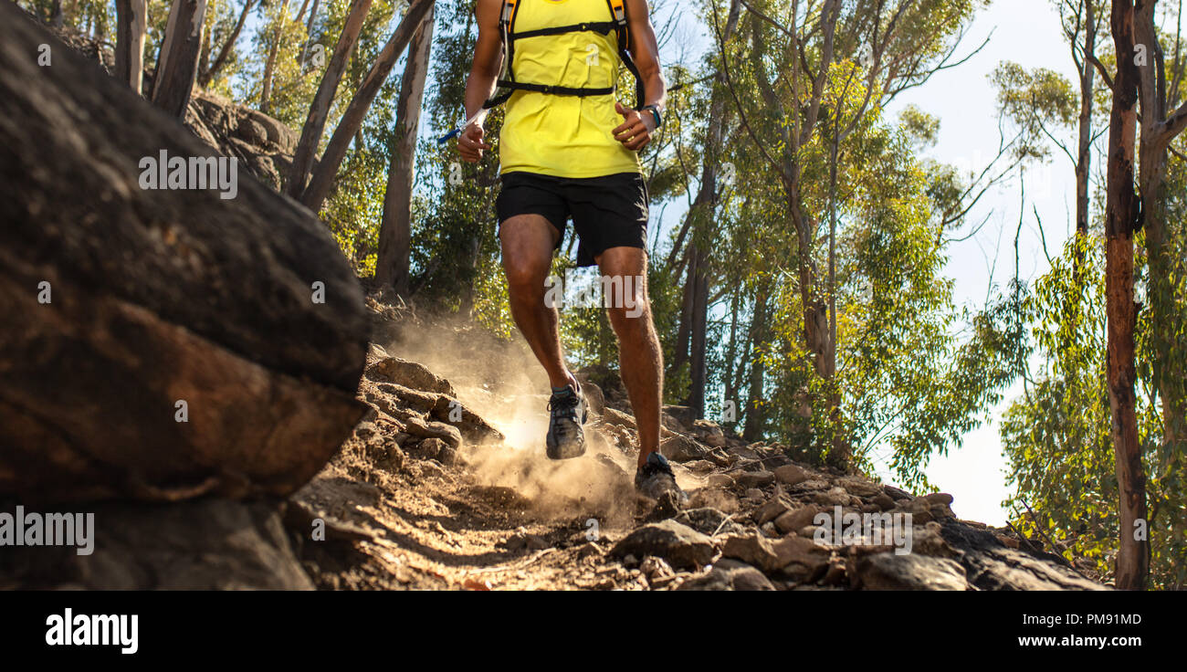 Low section of trail runner running on challenging rocky terrain. Male ...