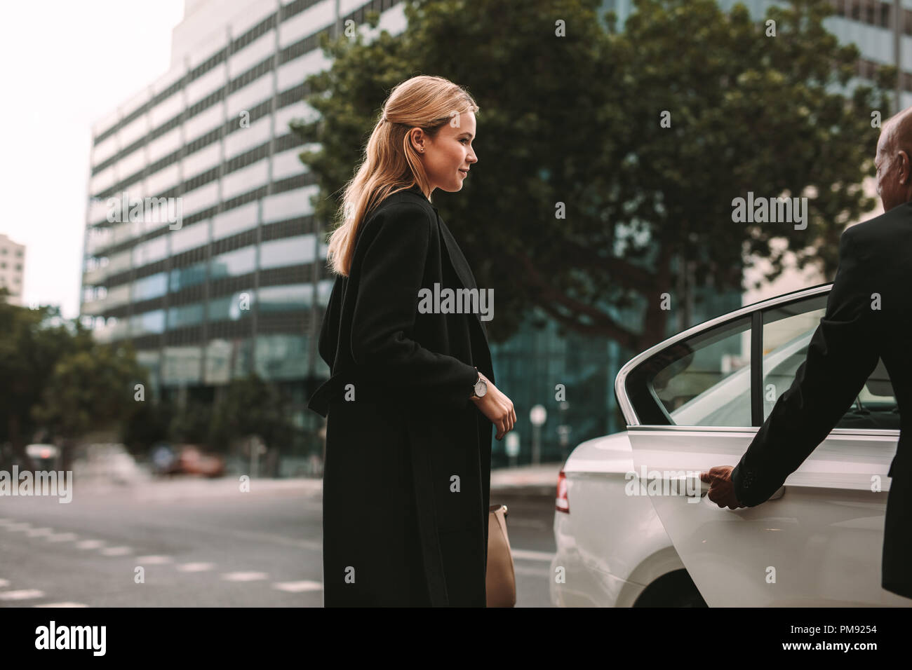 Young female commuter getting into a taxi. Businesswoman entering a ...