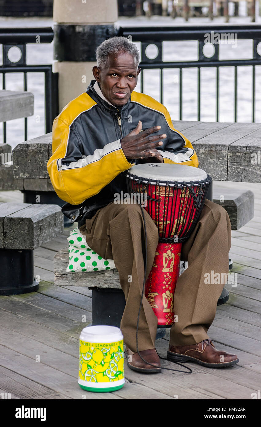 An African-American man plays a West African djembe drum at Waterfront ...