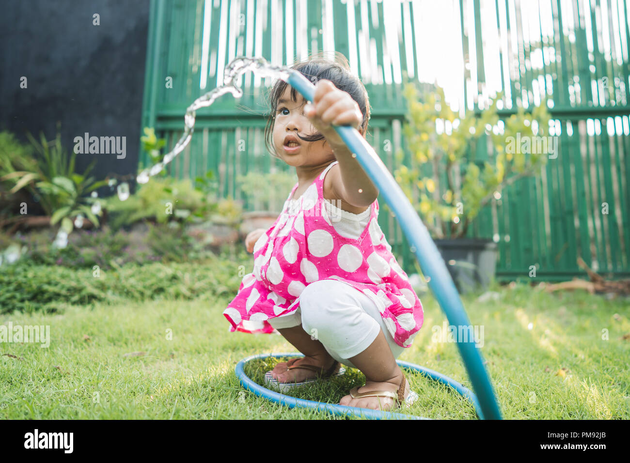 beautiful little daughter playing water with rubber tube Stock Photo ...