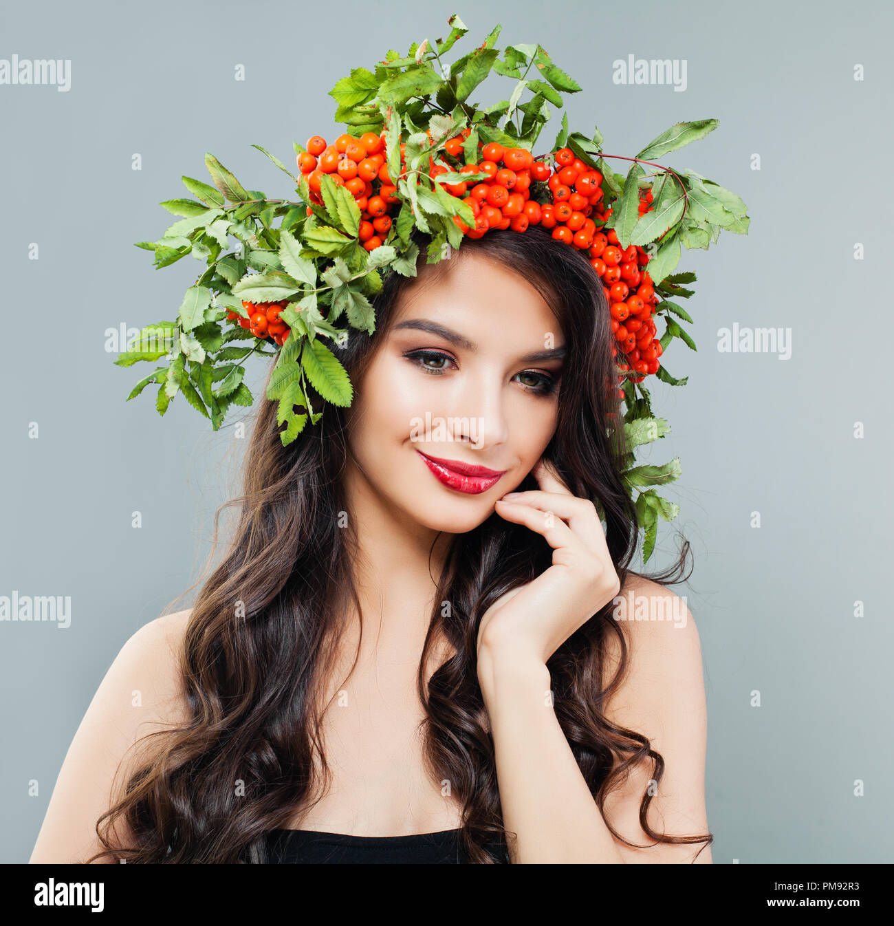 Young woman face with red lips makeup, long wavy hair and rowan berries ...