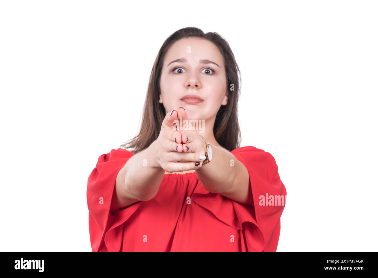 Surprised woman folds her arms like a gun and aims at the camera ...