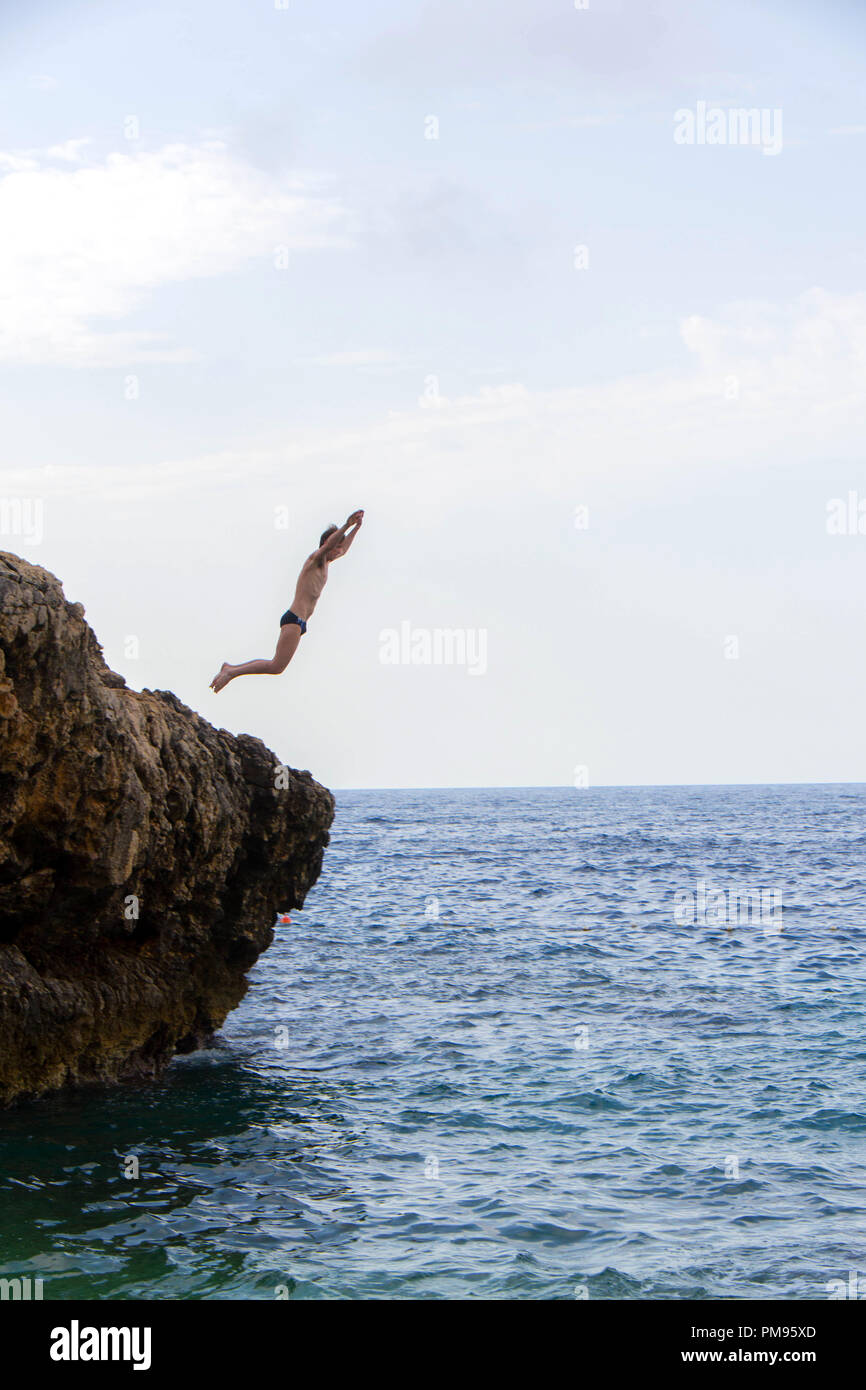 A man jumps into the sea from the cliff Stock Photo - Alamy
