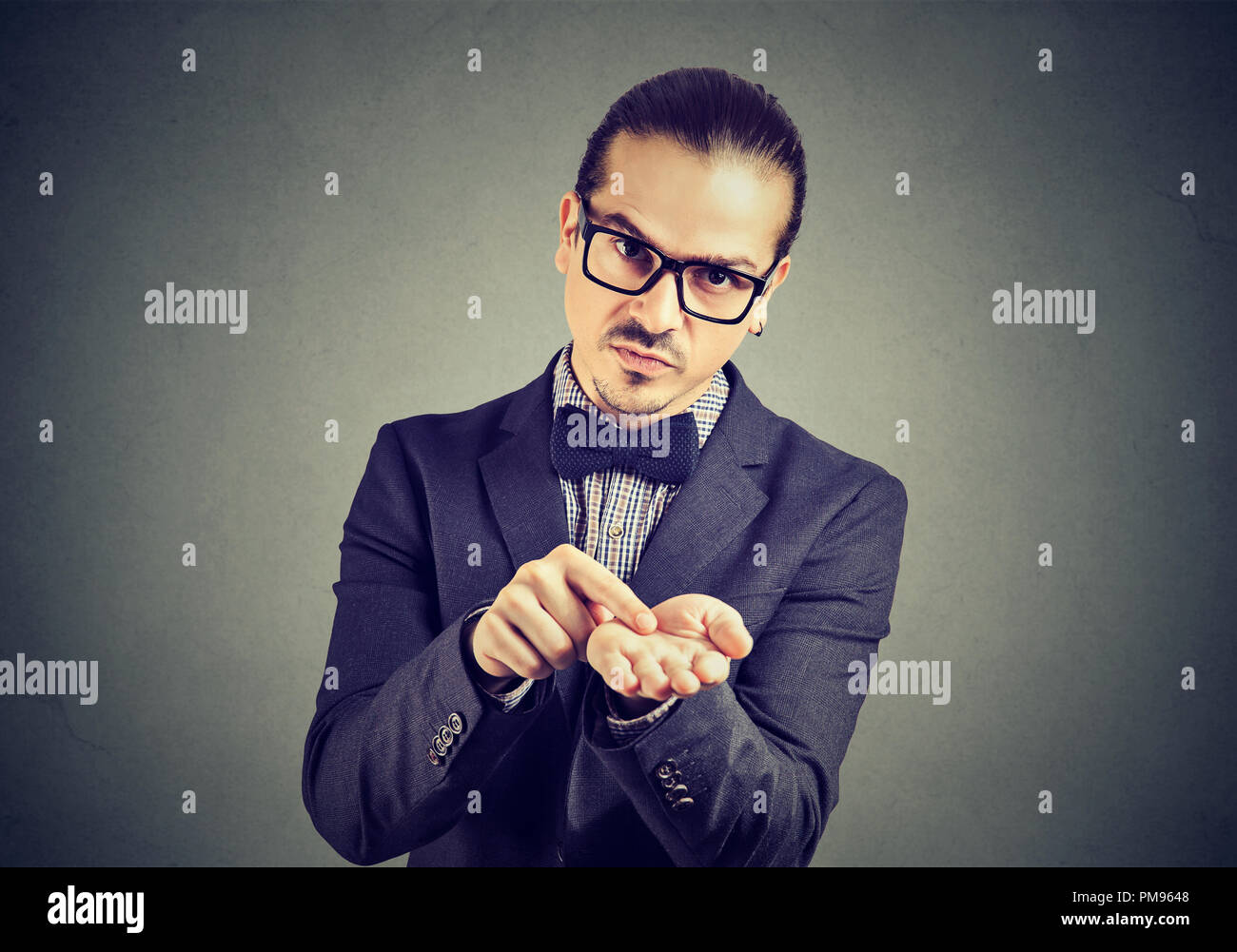 Young serious business man in glasses asking for more money to pay back ...