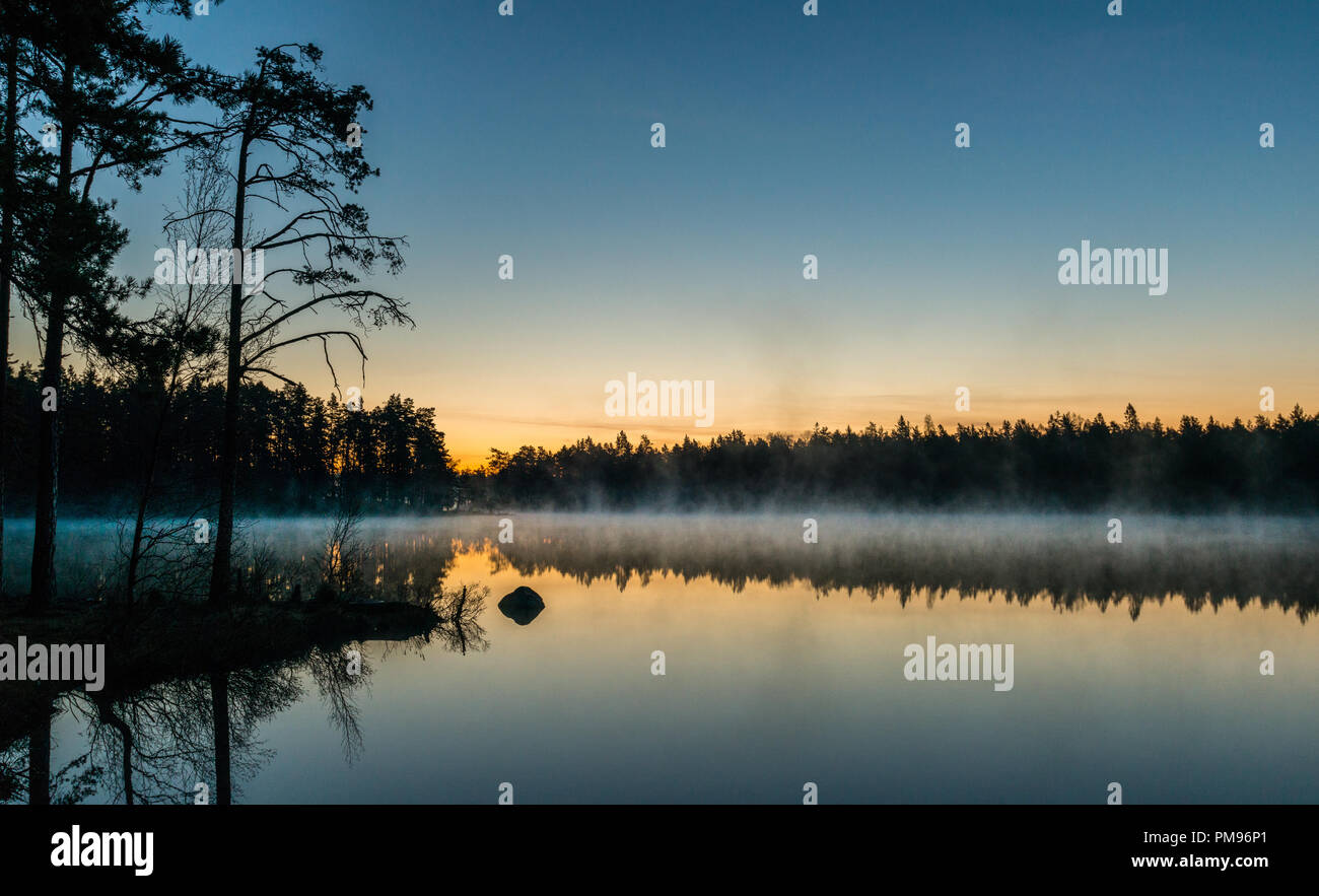 Calm lake with fog during sunrise Stock Photo - Alamy