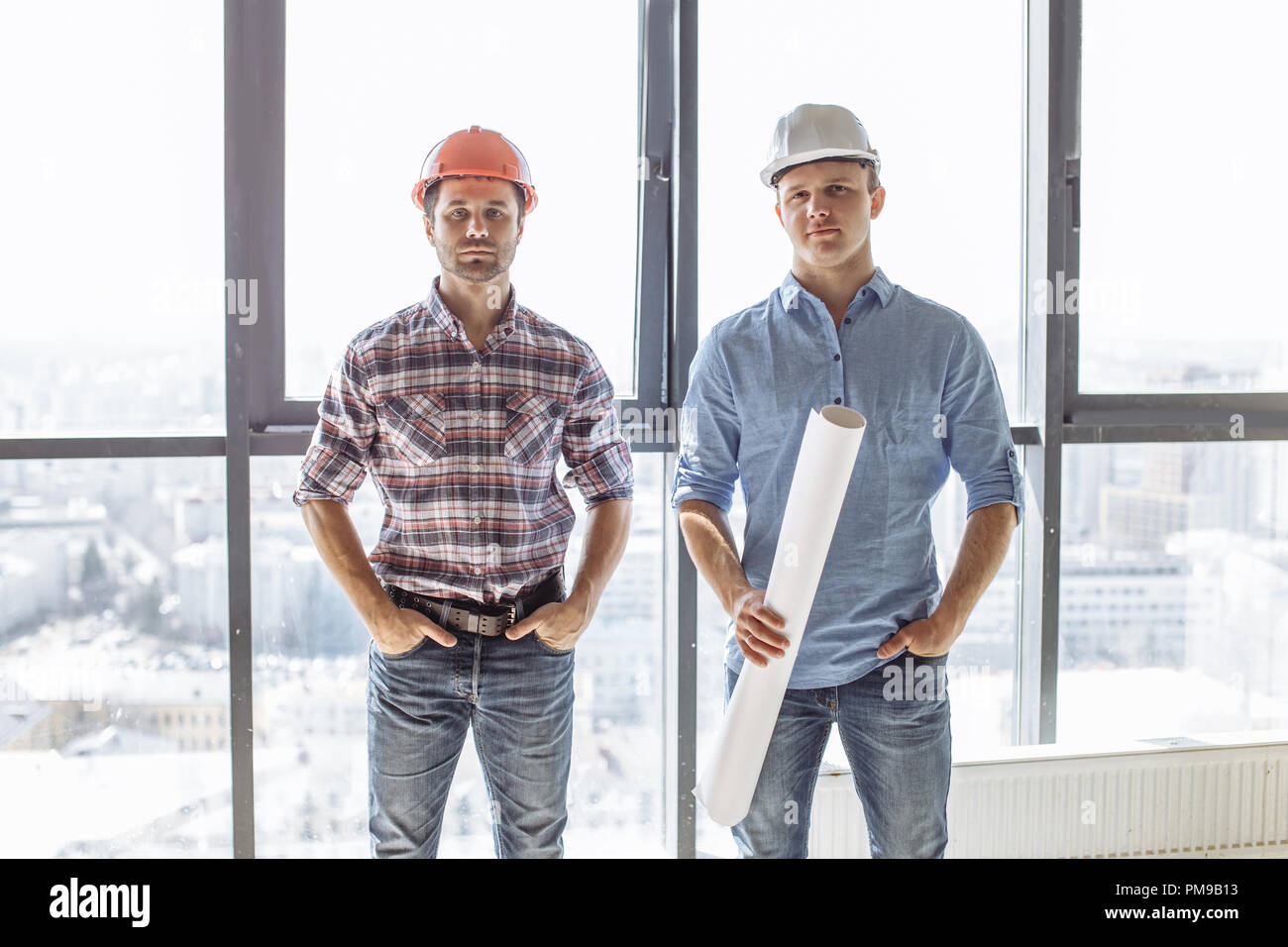talented handsome architects with blueprint are posing to the camera ...
