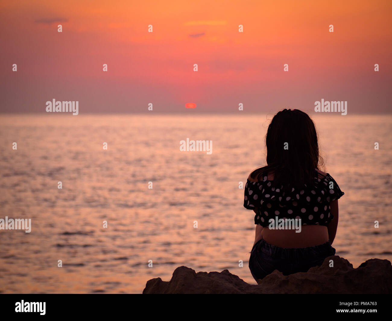 A young giel watches the sunset over San Antonio bay, Ibiza Stock Photo ...