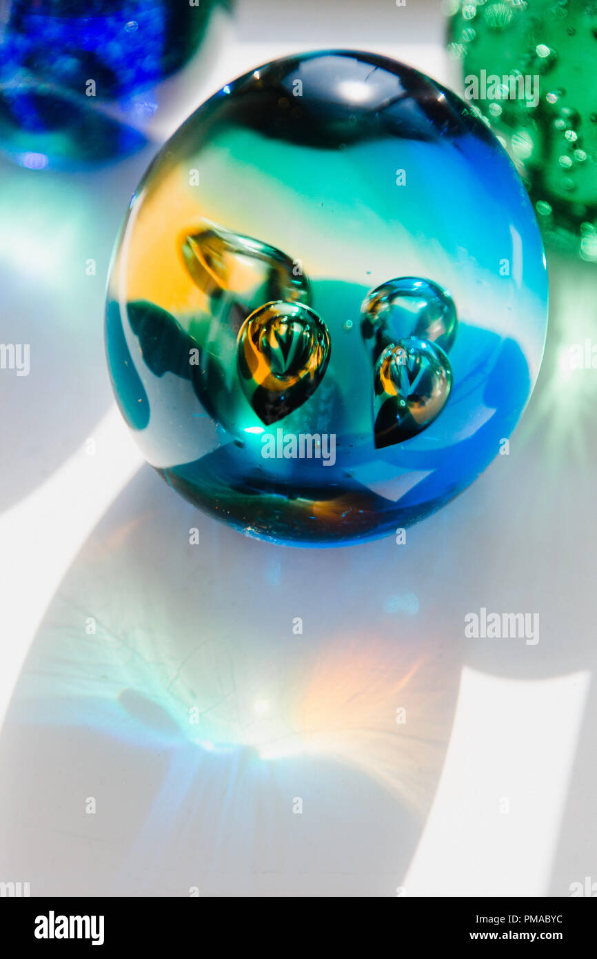 Pretty handblown glass paperweight with blue, orange and green colours ...