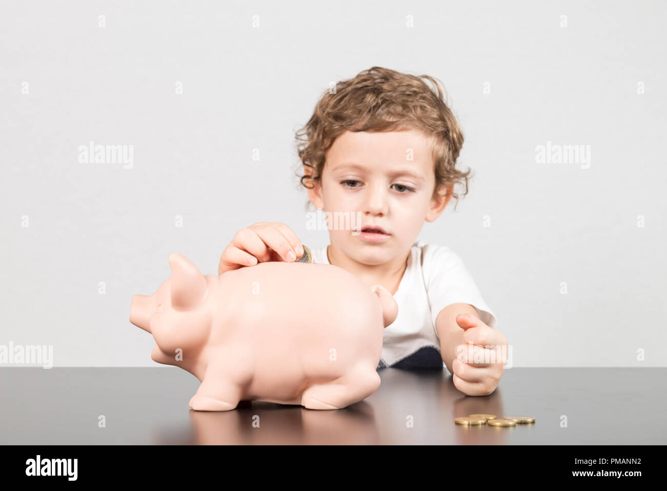 Child inserting coins in a piggy bank Stock Photo - Alamy