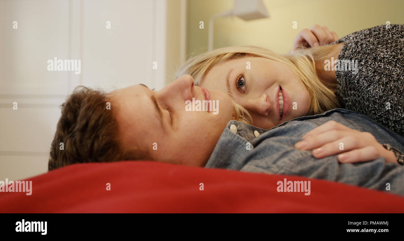 Happy young couple cuddling in bed together Stock Photo - Alamy