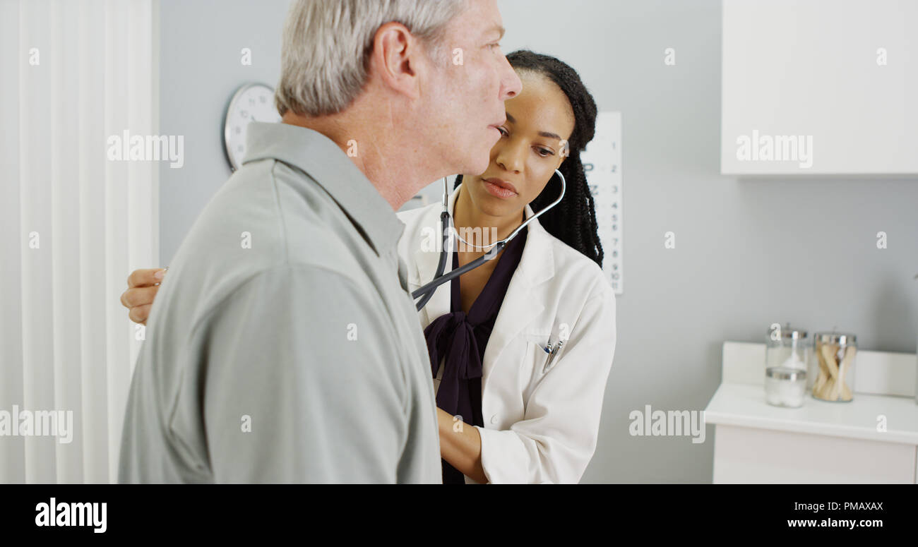 Black woman doctor listening to senior breathing Stock Photo - Alamy