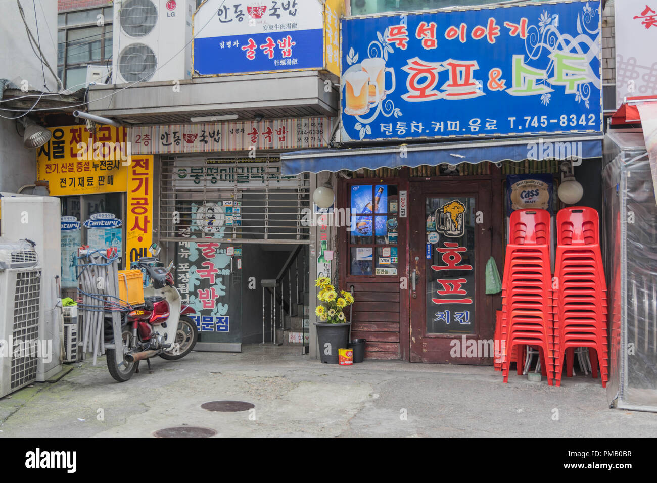 A store front with stacked red chairs, a scooter and colorful signs, in ...