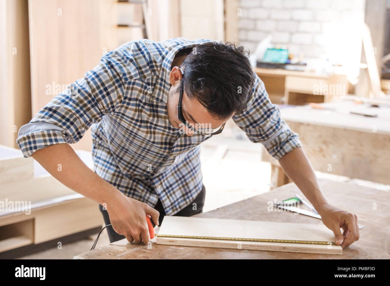 young carpenter measuring and marking the wood board Stock Photo - Alamy