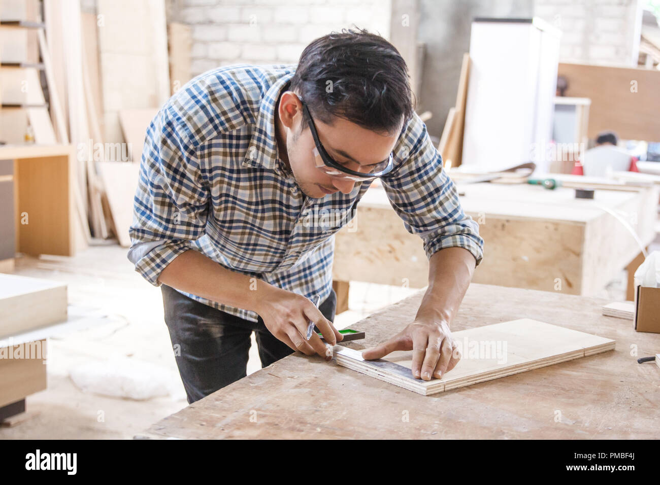 young carpenter measuring and marking the wood board Stock Photo - Alamy