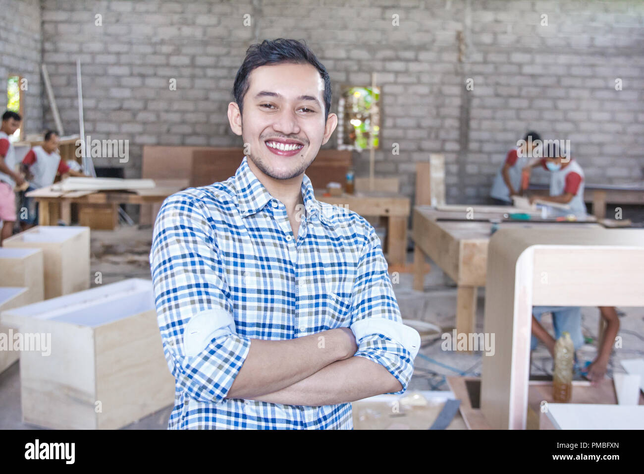 young carpenter smiling with arm crossed at carpenter workshop Stock ...