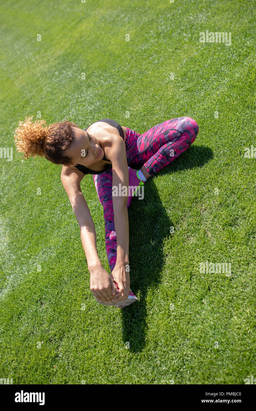 Young sportive woman doing stretching on grass Stock Photo - Alamy