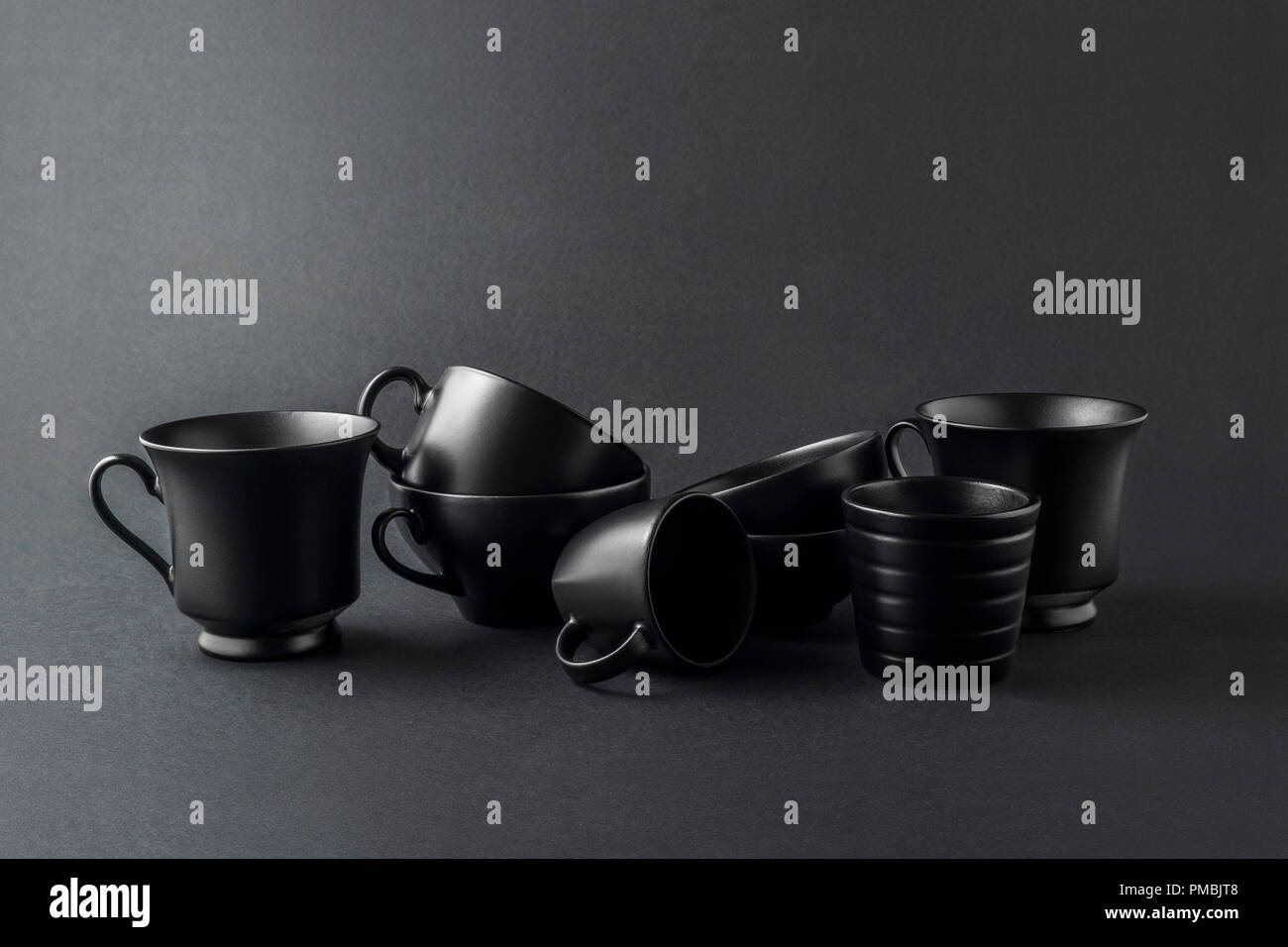 Creative concept photo of kitchenware, painted cups and mugs on black ...