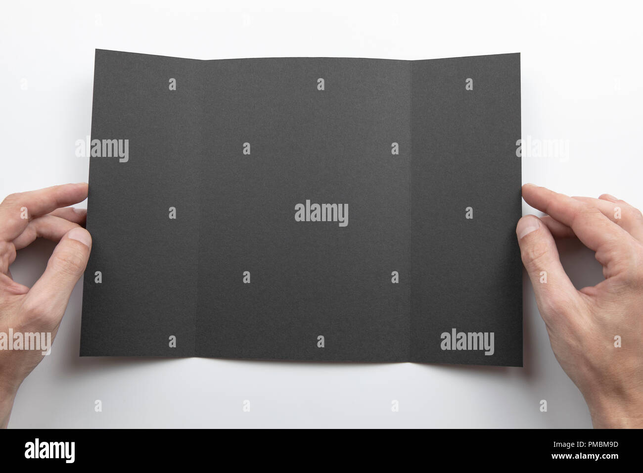 Mens hands holding empty black booklet on white background. View from ...