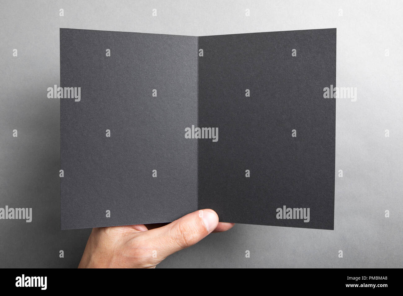 Mens hand holding empty black booklet on gray background. View from ...