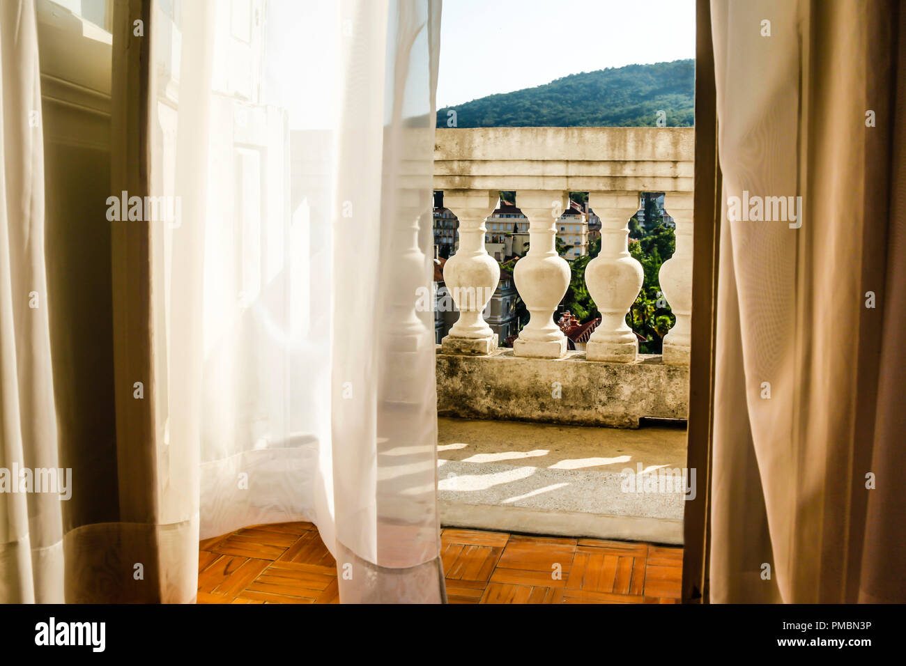 Flowing net curtains blow in the wind as they lead out to the old ...