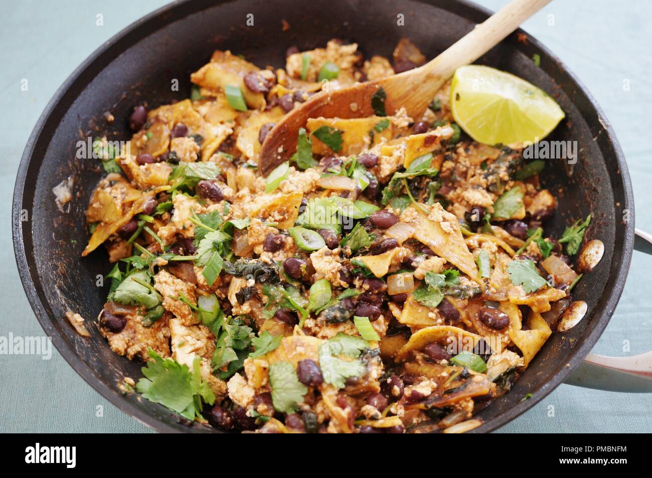 Vegan tofu scramble chilaquiles with beans, scallions and lime Stock ...