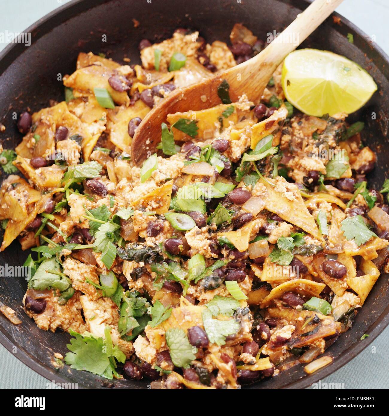 Vegan tofu scramble chilaquiles with beans, scallions and lime Stock ...