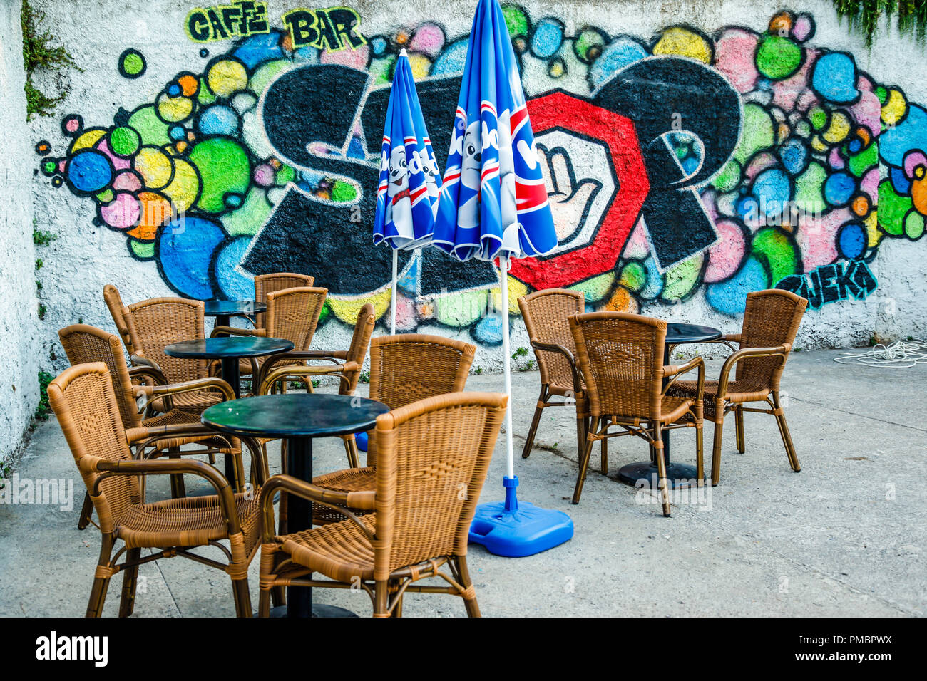 Empty tables and chairs outside a pop cafe bar with graffiti art on the ...