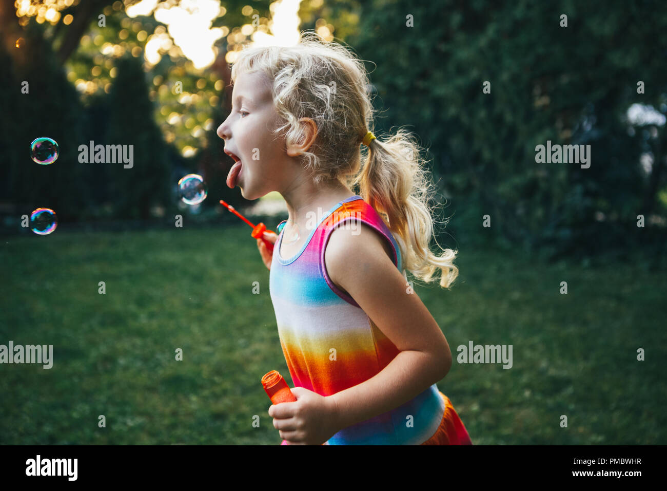 Kid child trying to catch eat soap bubbles with tongue. Candid portrait ...