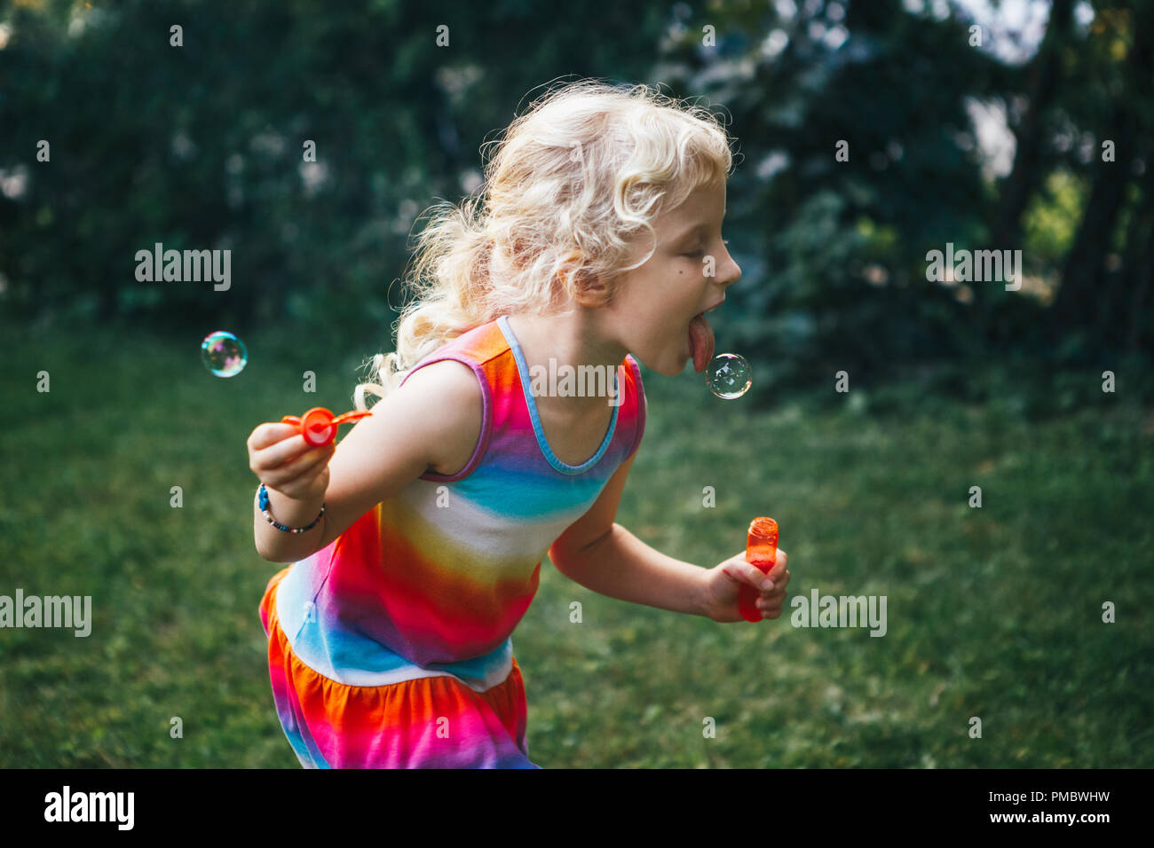 Kid child trying to catch eat soap bubbles with tongue. Candid portrait ...