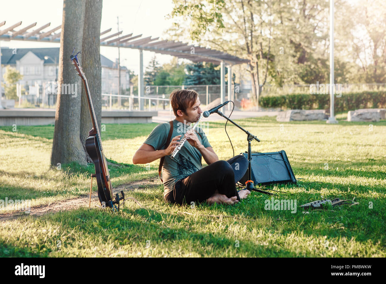 Portrait of white Caucasian male musician playing flute in park outside ...