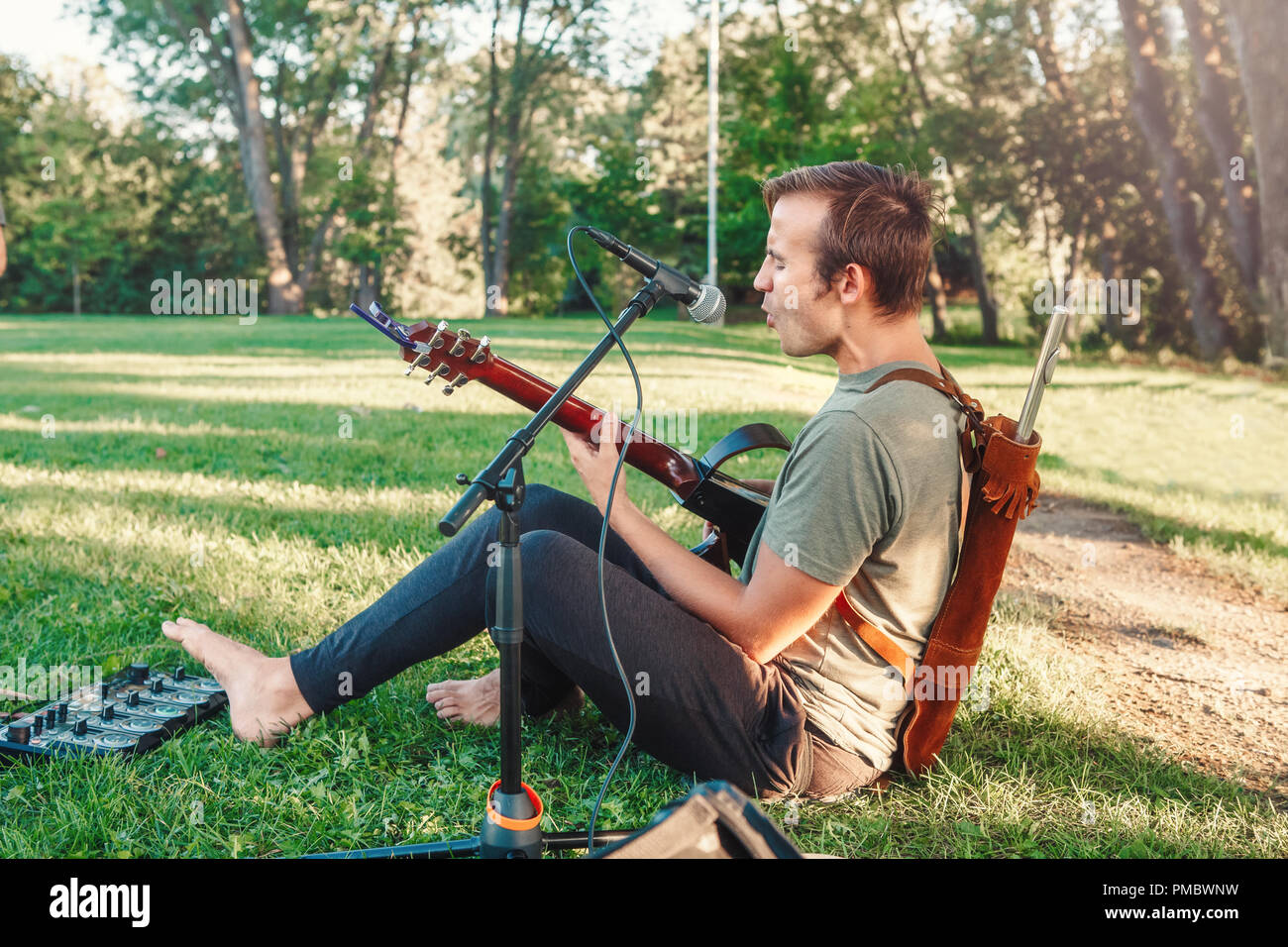 Portrait of white Caucasian male musician playing guitar in park ...