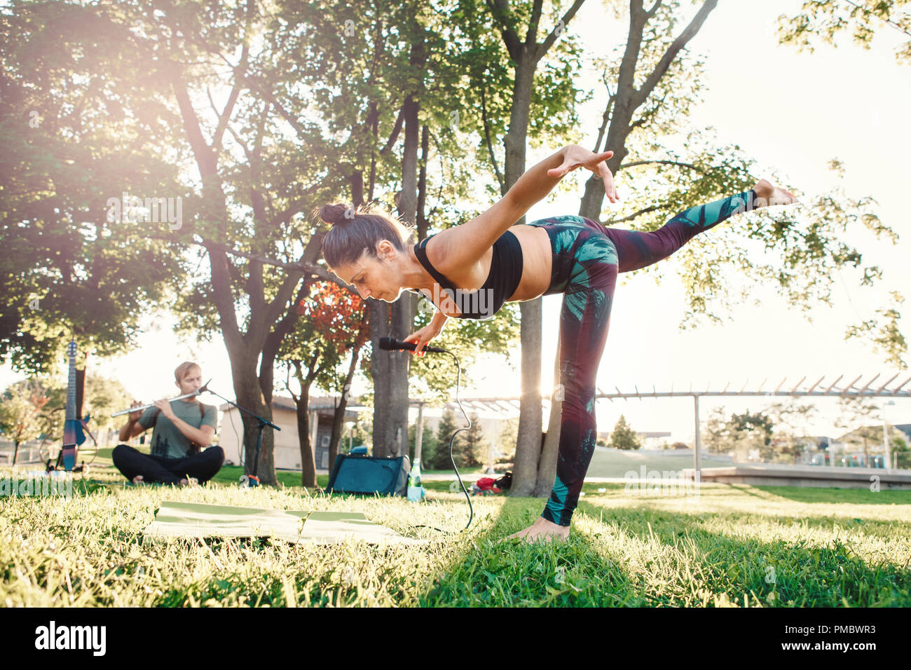 White Caucasian middle age woman doing yoga in park outside on sunset ...