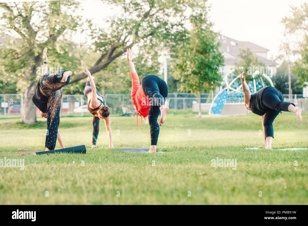Group of many Caucasian people doing yoga in park outside on sunset ...